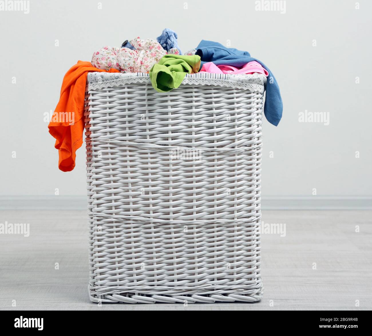 Full laundry basket on wooden floor on gray background Stock Photo - Alamy
