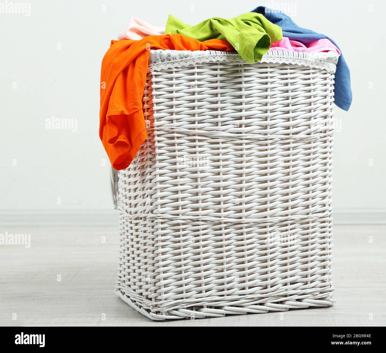 Full laundry basket on wooden floor on gray background Stock Photo - Alamy