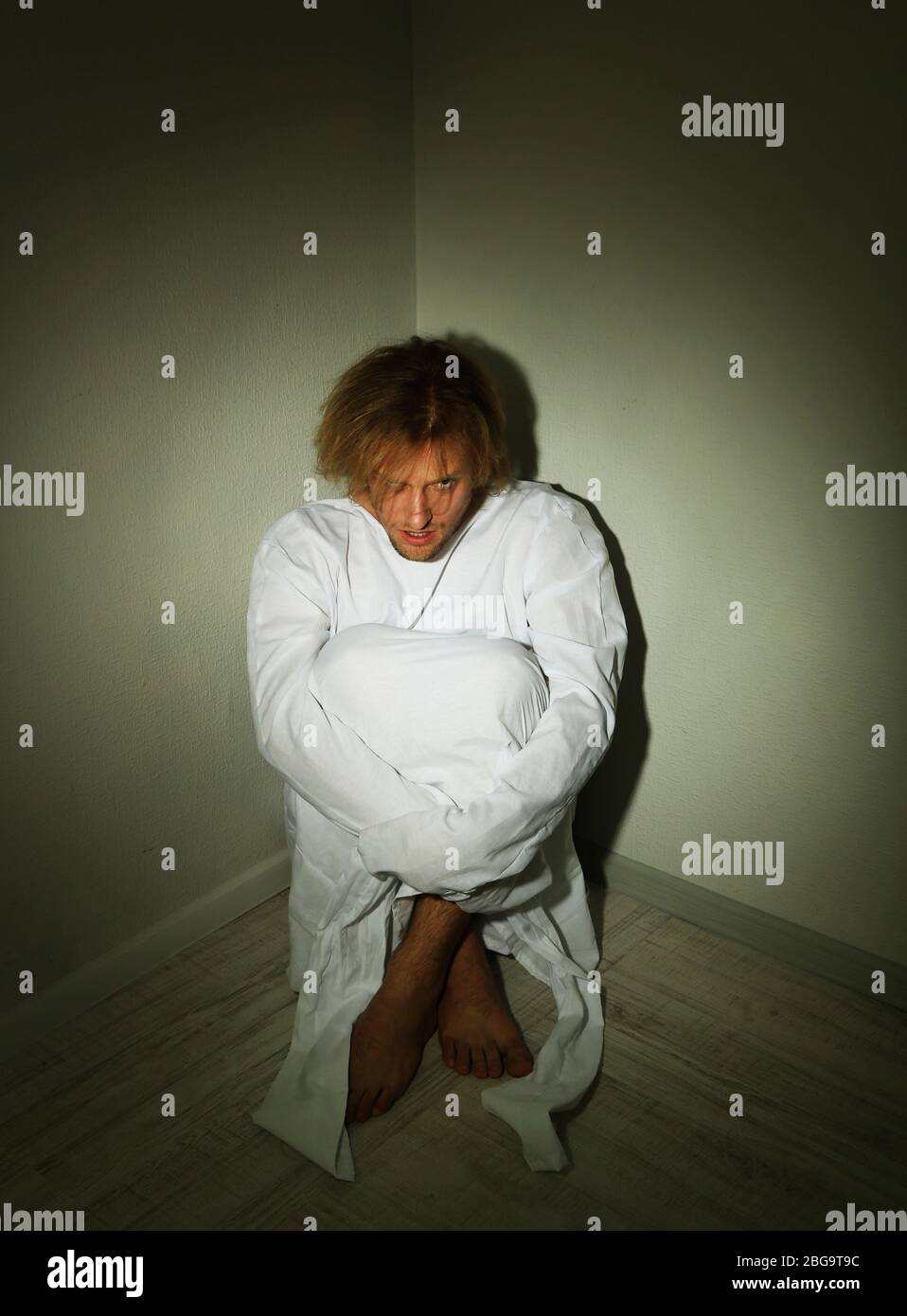 Mentally ill man in strait-jacket in room corner Stock Photo - Alamy