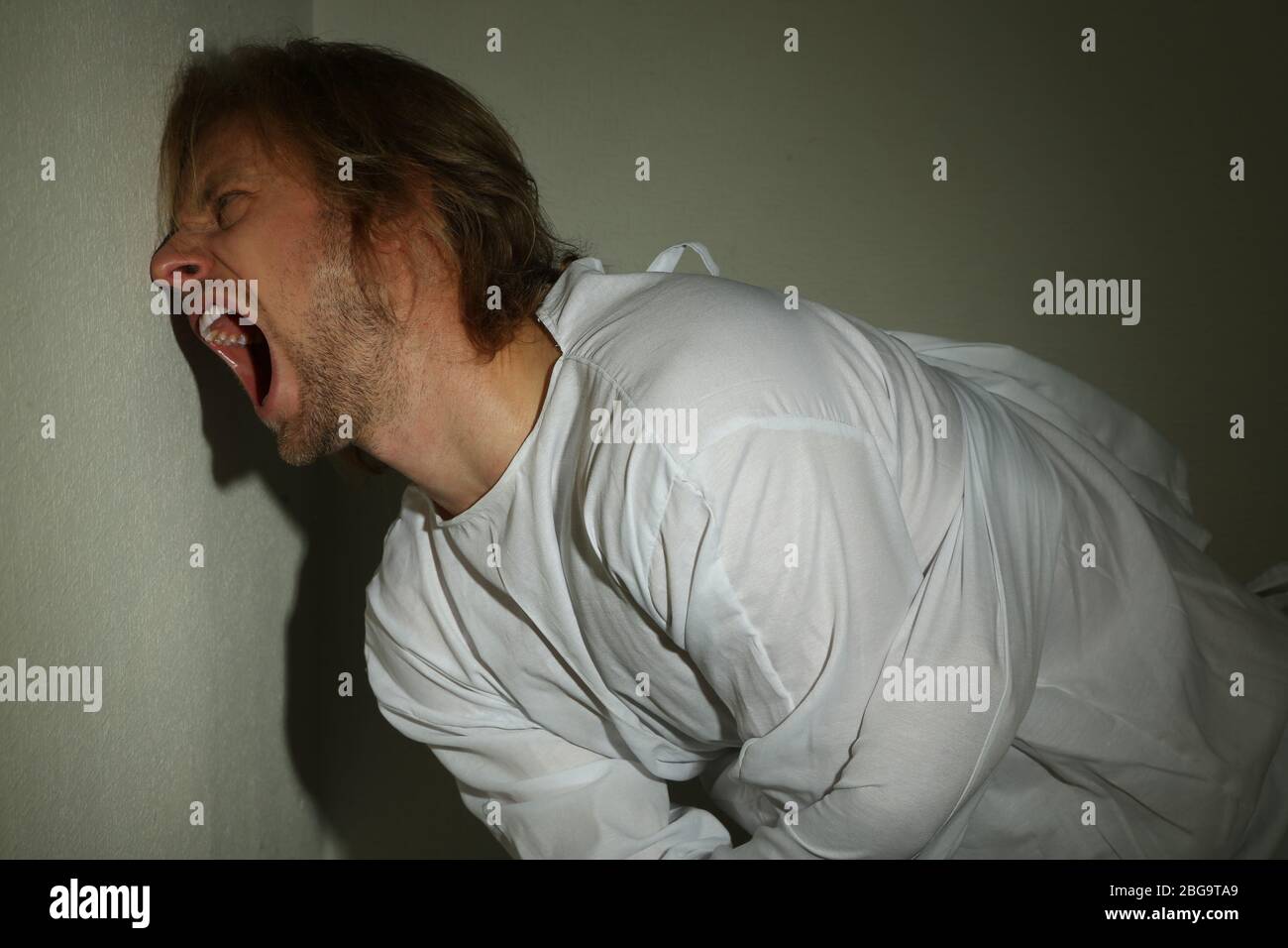 Mentally ill man in strait-jacket in room corner Stock Photo - Alamy