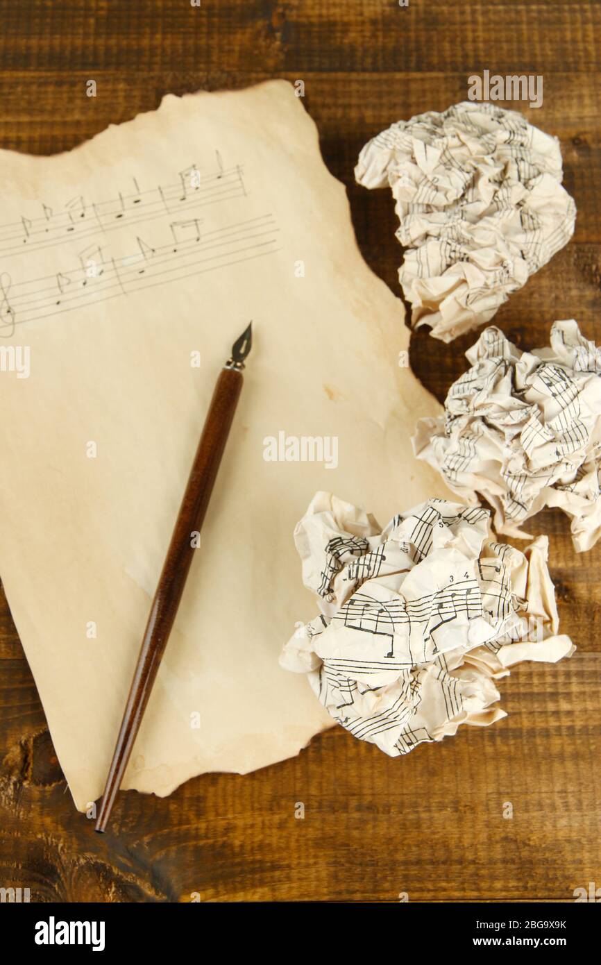 Crumpled paper balls with ink pen and music sheet on wooden background ...