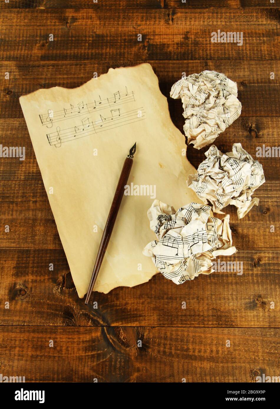 Crumpled paper balls with ink pen and music sheet on wooden background ...