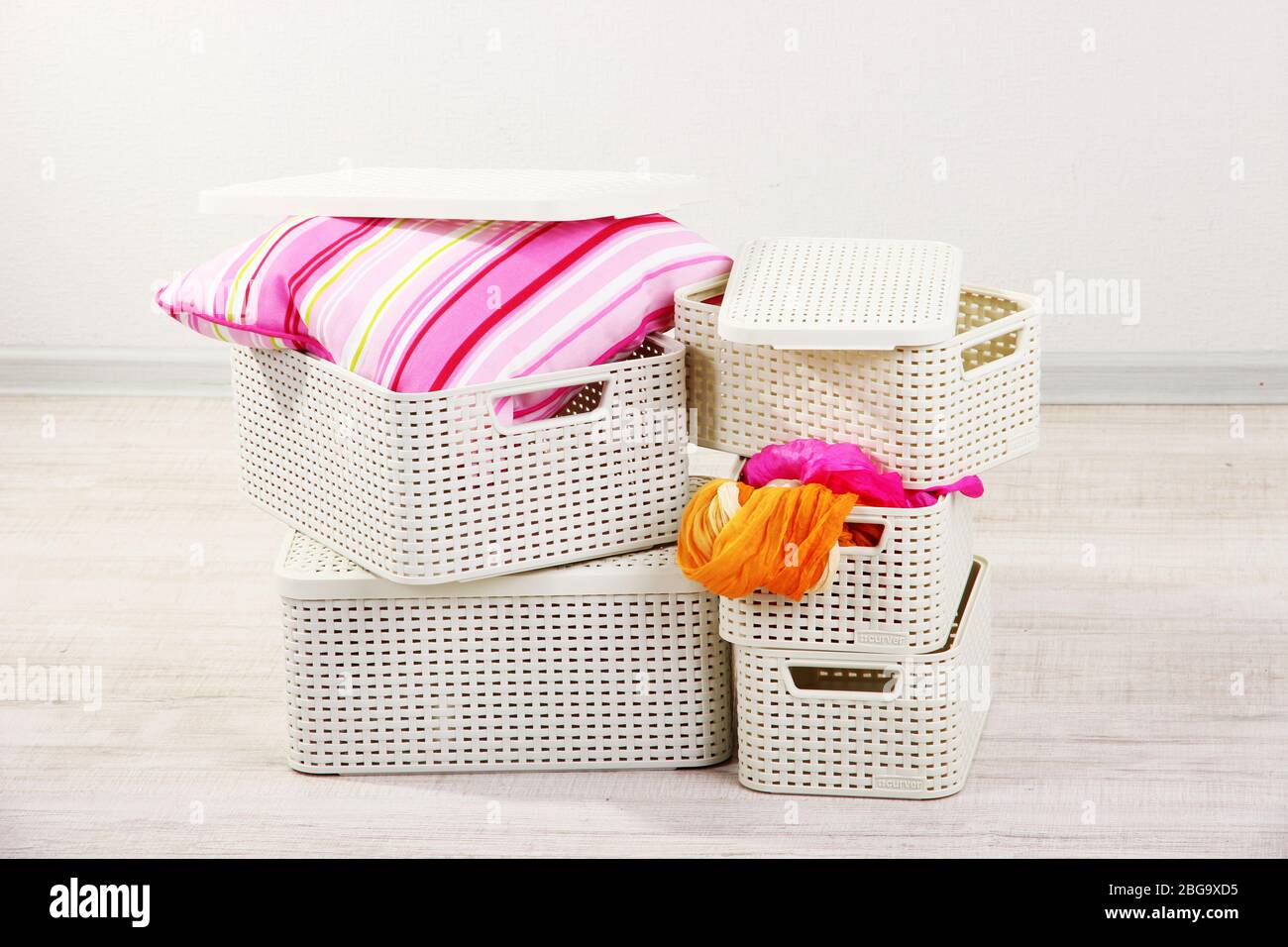 Plastic baskets with things in floor on room background Stock Photo - Alamy