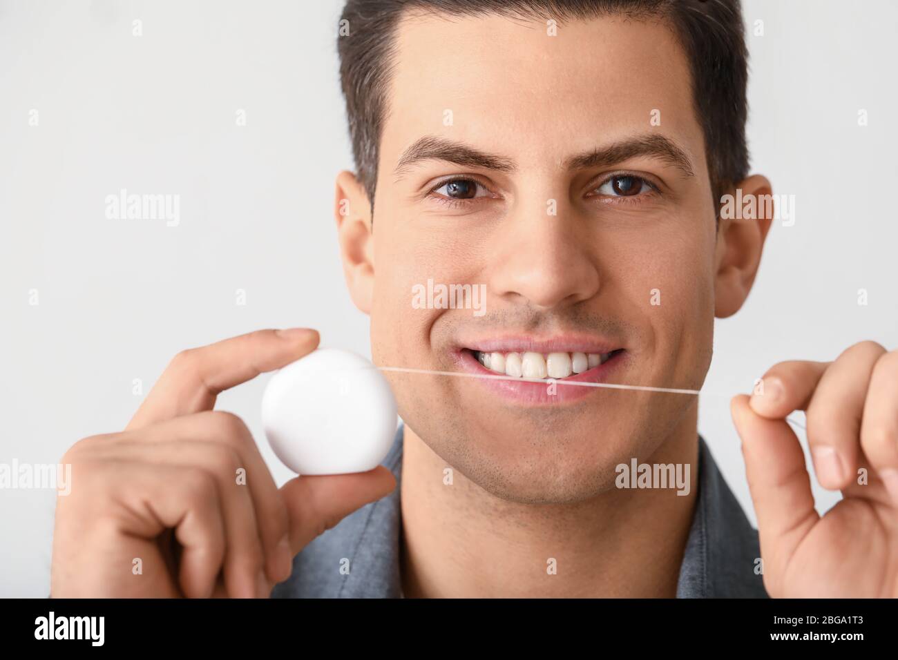 Young man with floss on light background Stock Photo - Alamy