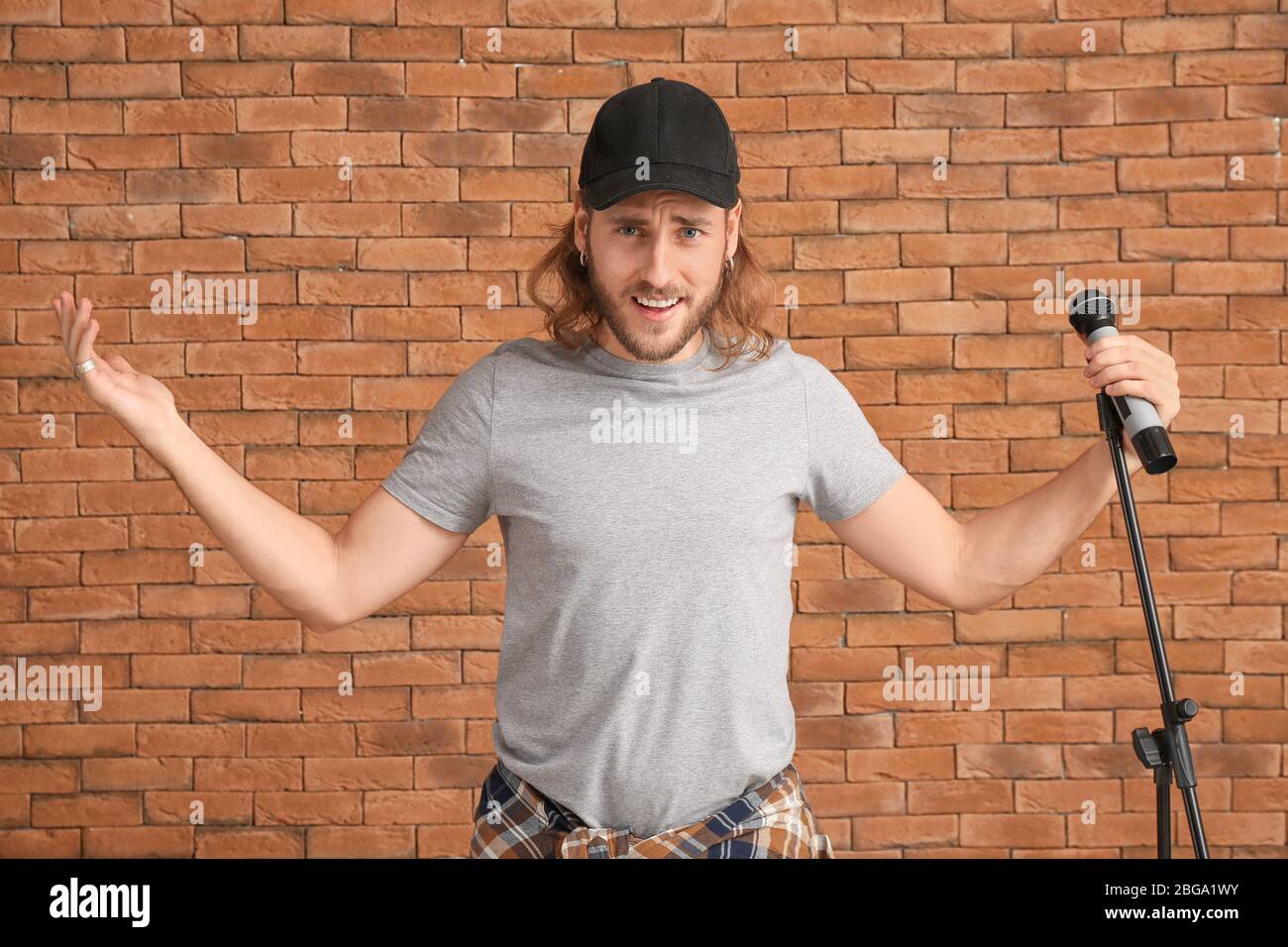 Young male singer on brick background Stock Photo - Alamy