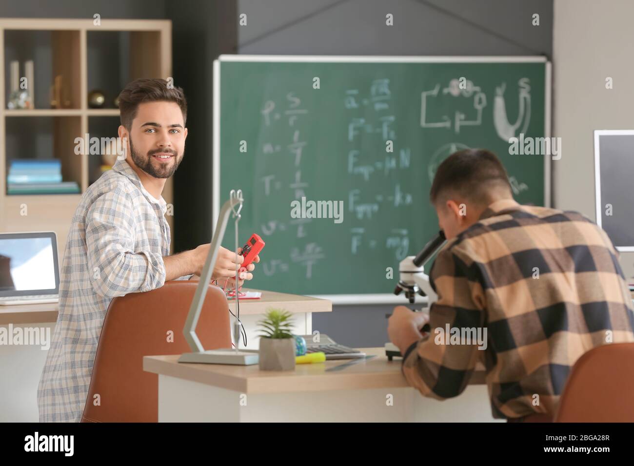 Young man at physics lesson in classroom Stock Photo - Alamy