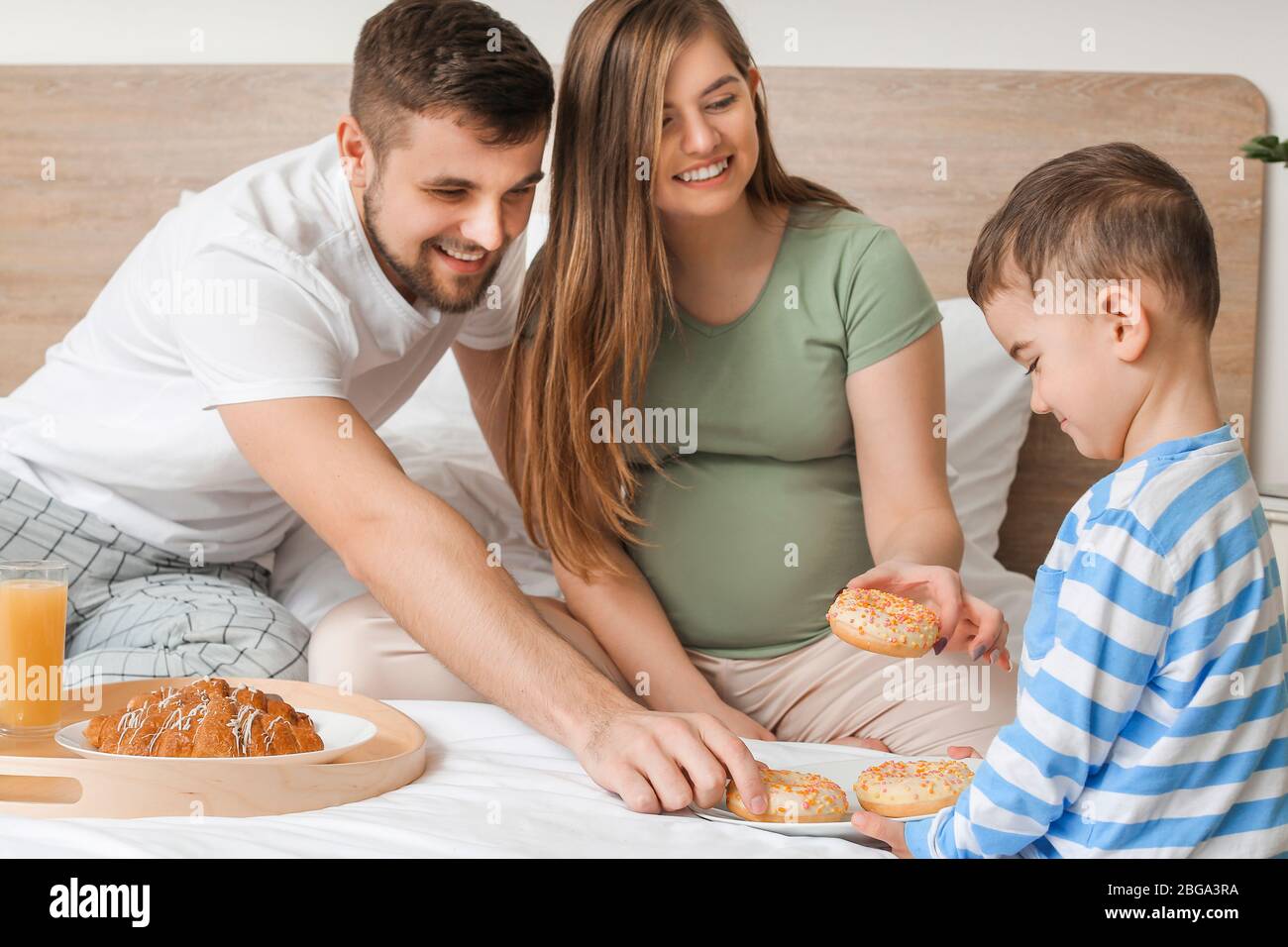 Happy family eating pastry in bedroom Stock Photo - Alamy