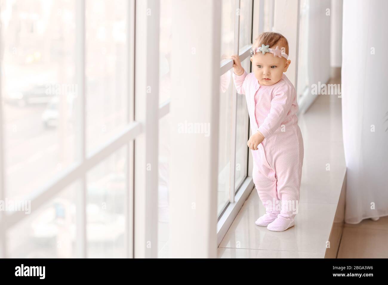 Little baby near window at home. Child in danger Stock Photo - Alamy