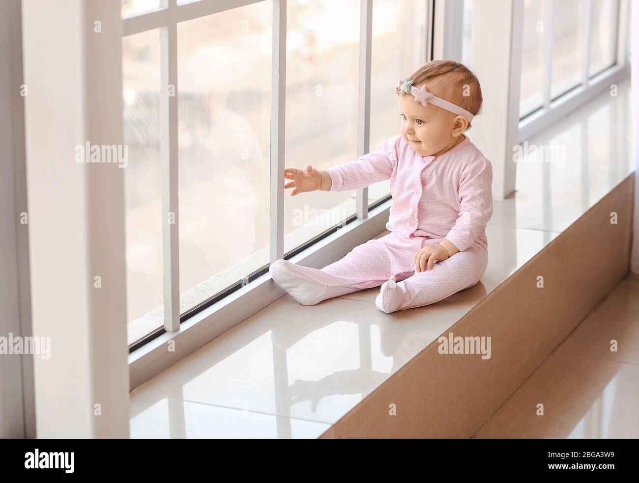 Little baby near window at home. Child in danger Stock Photo - Alamy