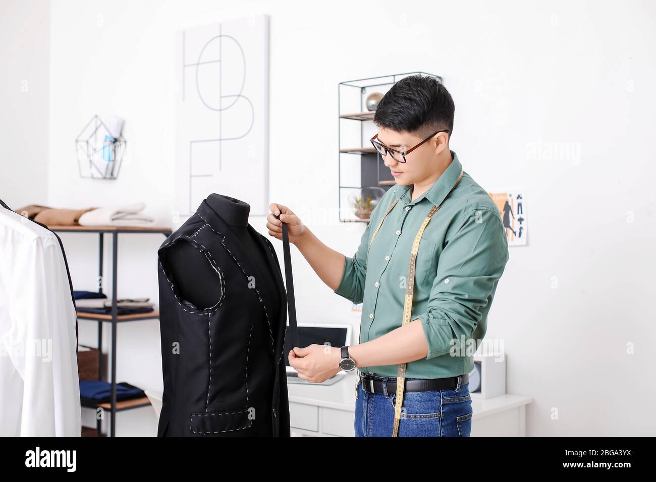 Young male Asian stylist near mannequin in studio Stock Photo - Alamy
