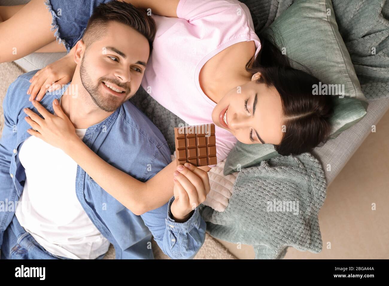 Beautiful young couple eating chocolate at home Stock Photo - Alamy
