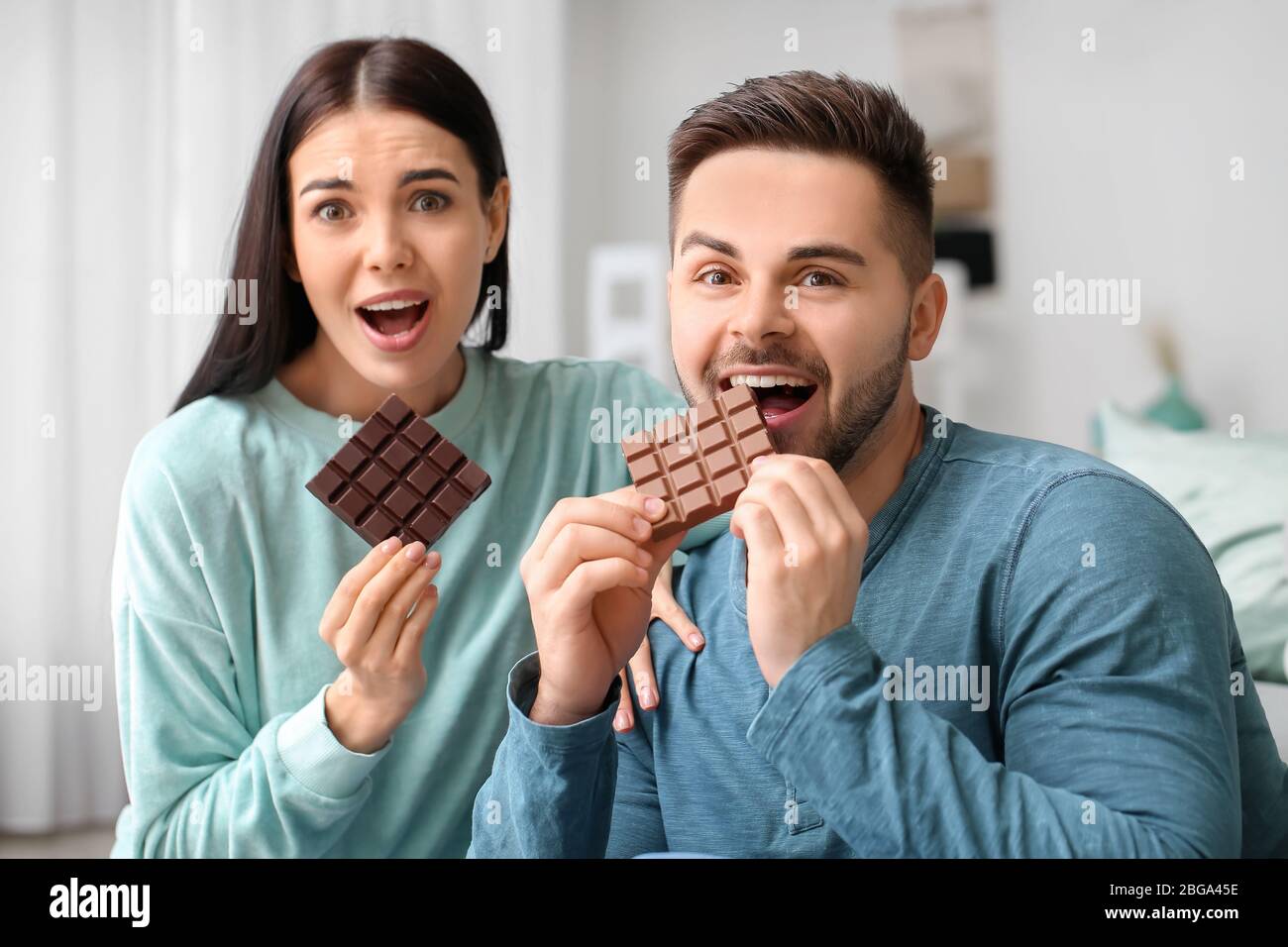 Emotional young couple eating chocolate at home Stock Photo - Alamy