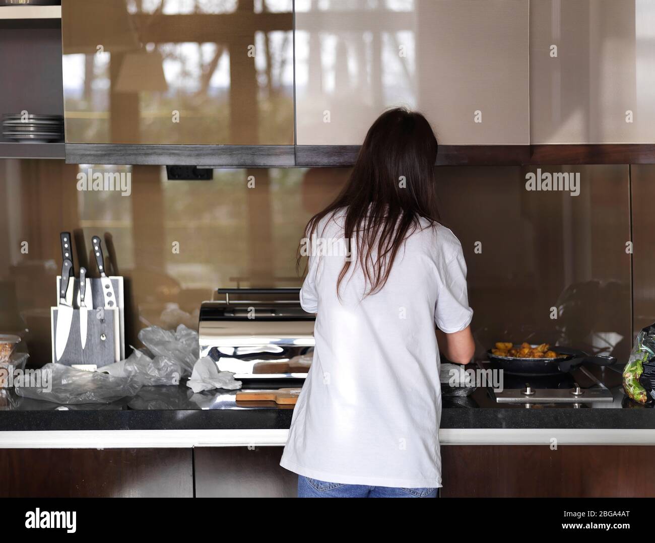 A woman with dark long hair cooking in a modern kitchen Stock Photo - Alamy