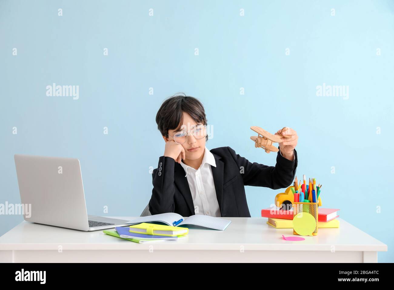 Little boy unwilling to do homework against color background Stock ...