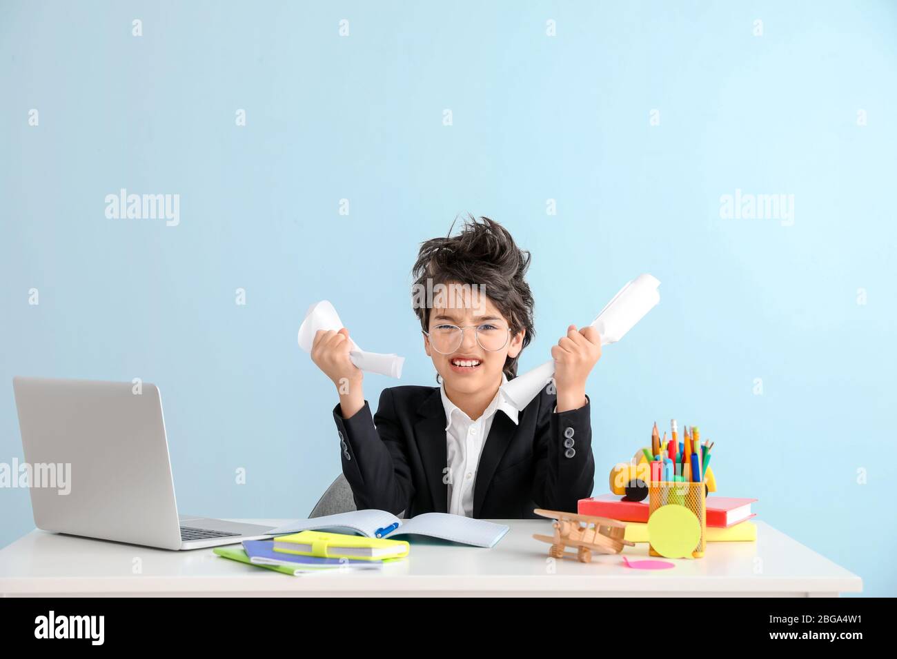 Stressed little boy doing homework against color background Stock Photo ...