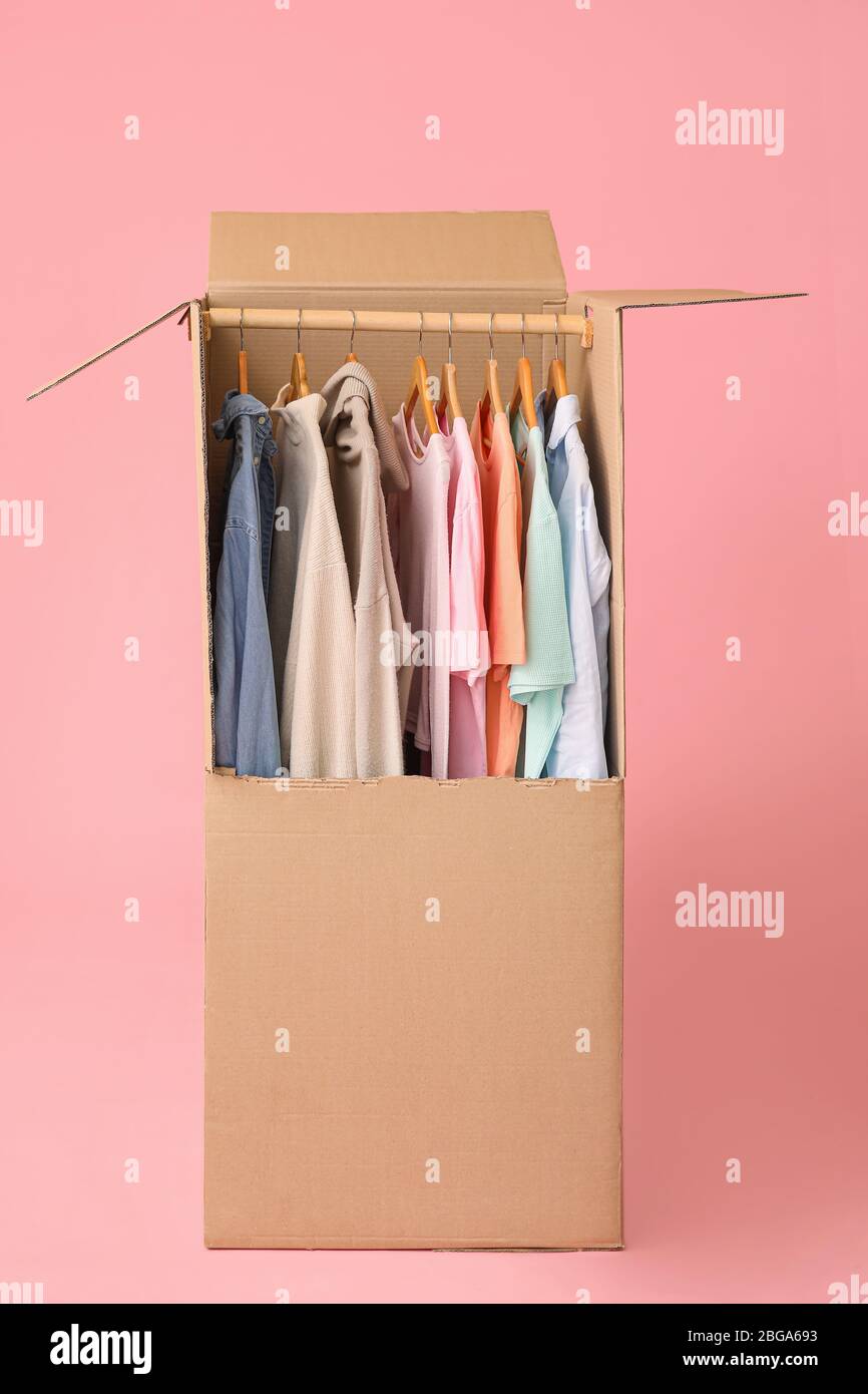 Moving box with clothes on color background Stock Photo - Alamy