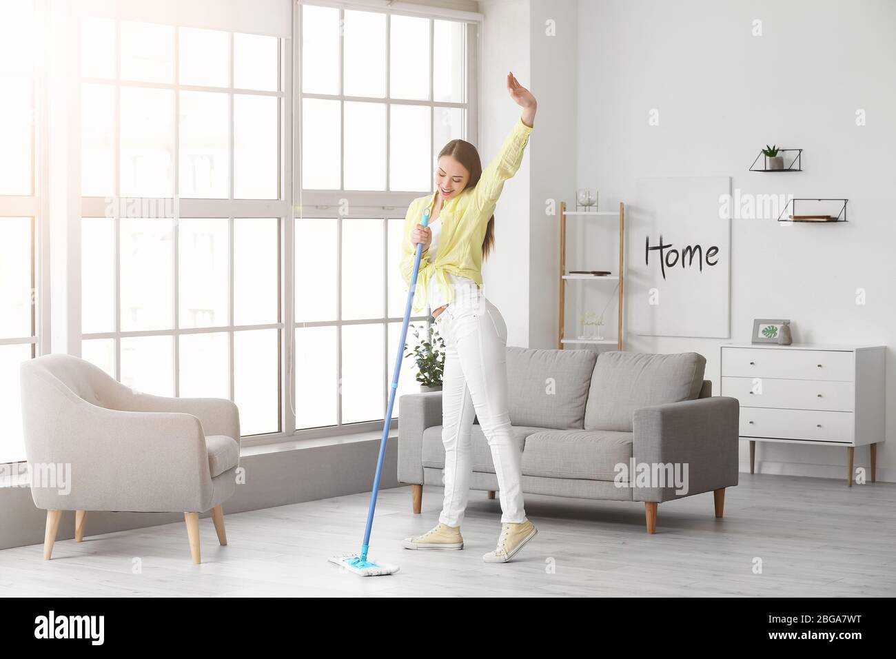 Young woman having fun while mopping floor in room Stock Photo - Alamy