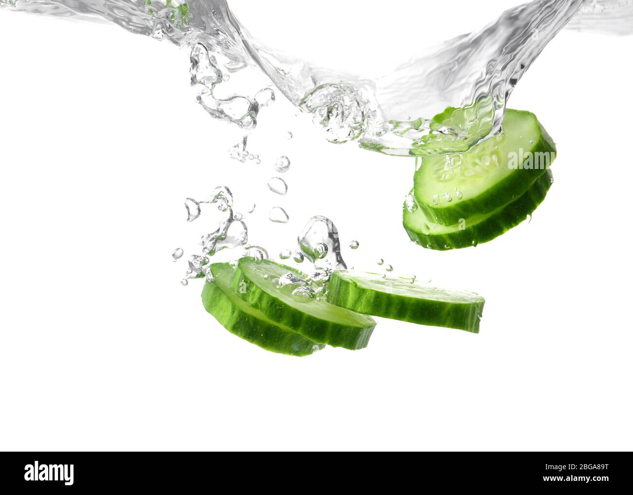 Falling of fresh cucumber slices into water against white background Stock Photo - Alamy