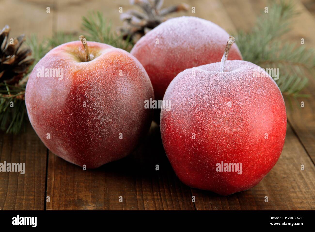 Red frosted apples with fir branch and bumps on wooden background Stock ...