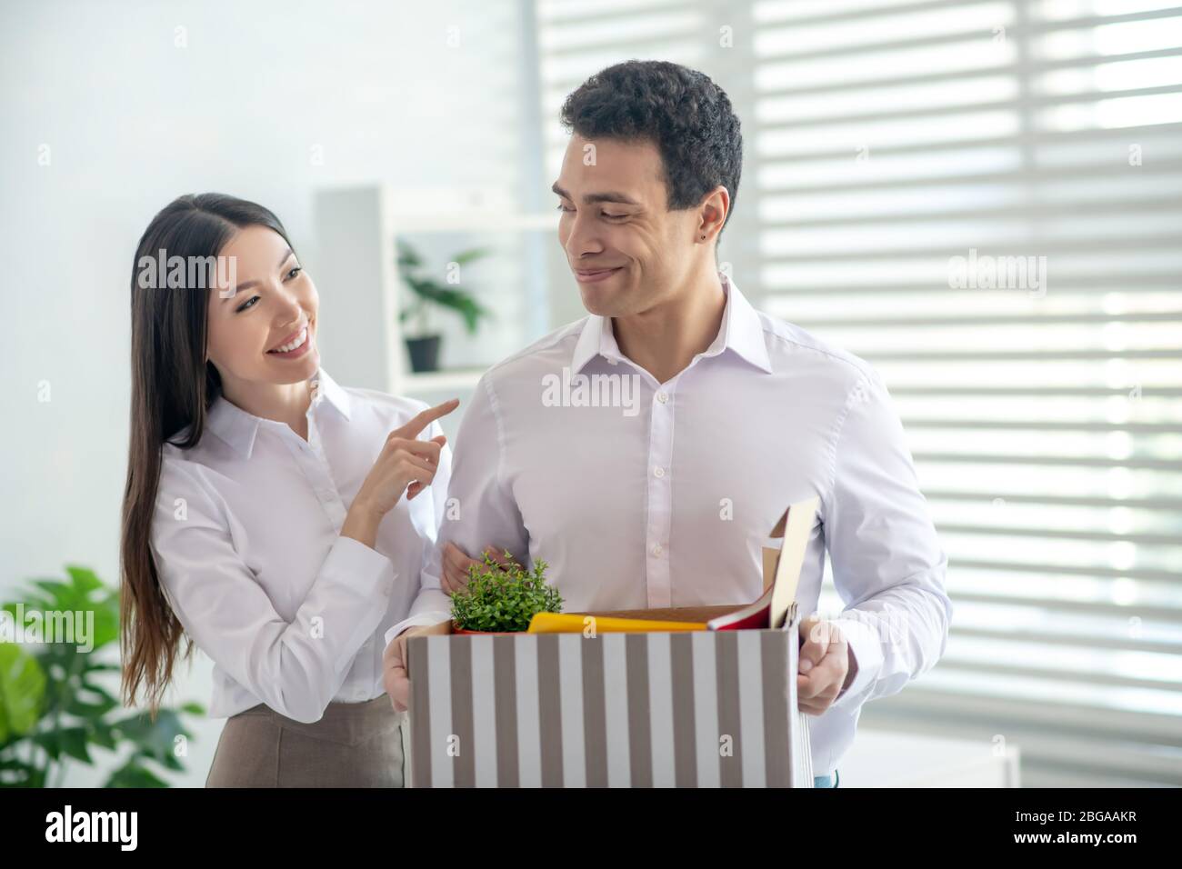 Smiling dark-haired woman touching shoulder of her colleague Stock ...