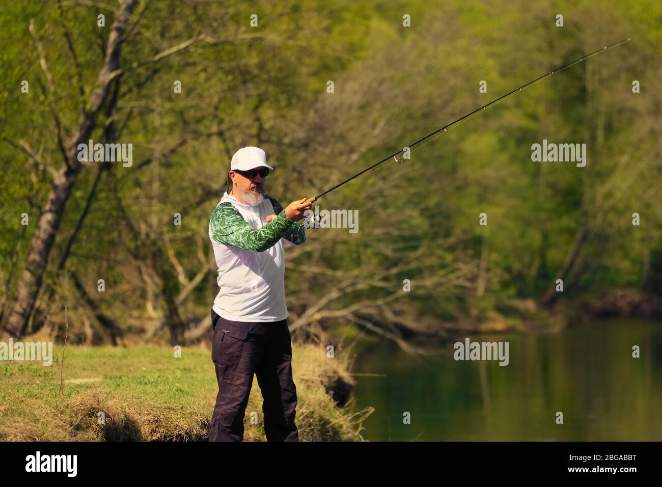Man fish with spinning on river bank, casting lure. Outdoor weekend ...