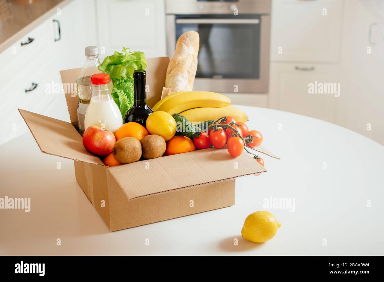 A box of different food, fruit, vegetables, milk on the kitchen. Safe ...