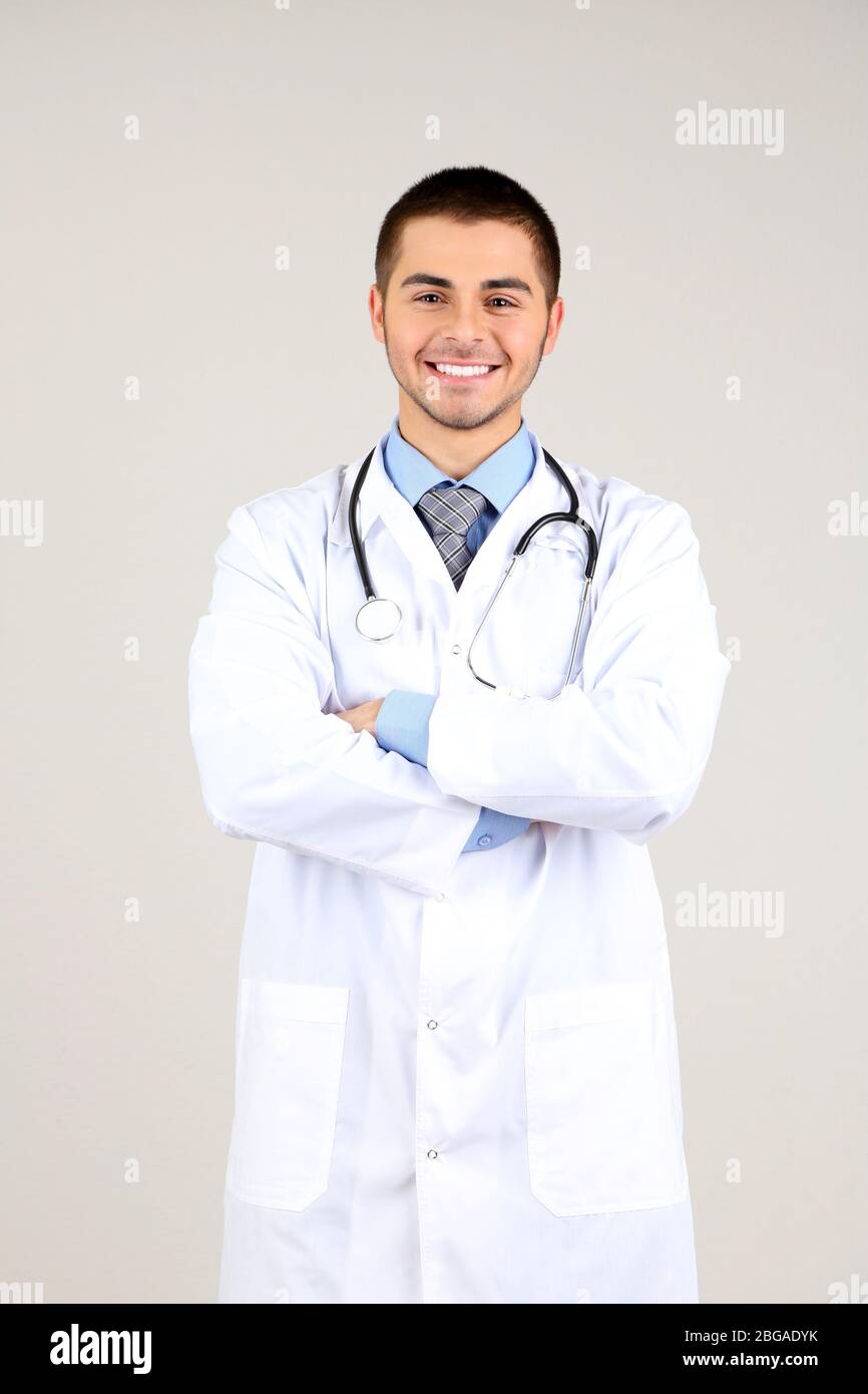 Male Doctor standing on gray background Stock Photo - Alamy