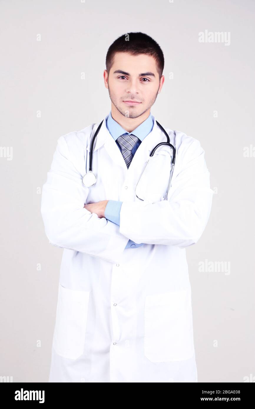 Male Doctor standing on gray background Stock Photo - Alamy
