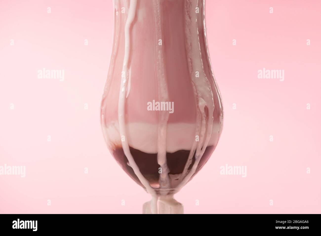 Glass of strawberry milkshake with ice cream dripping on pink ...