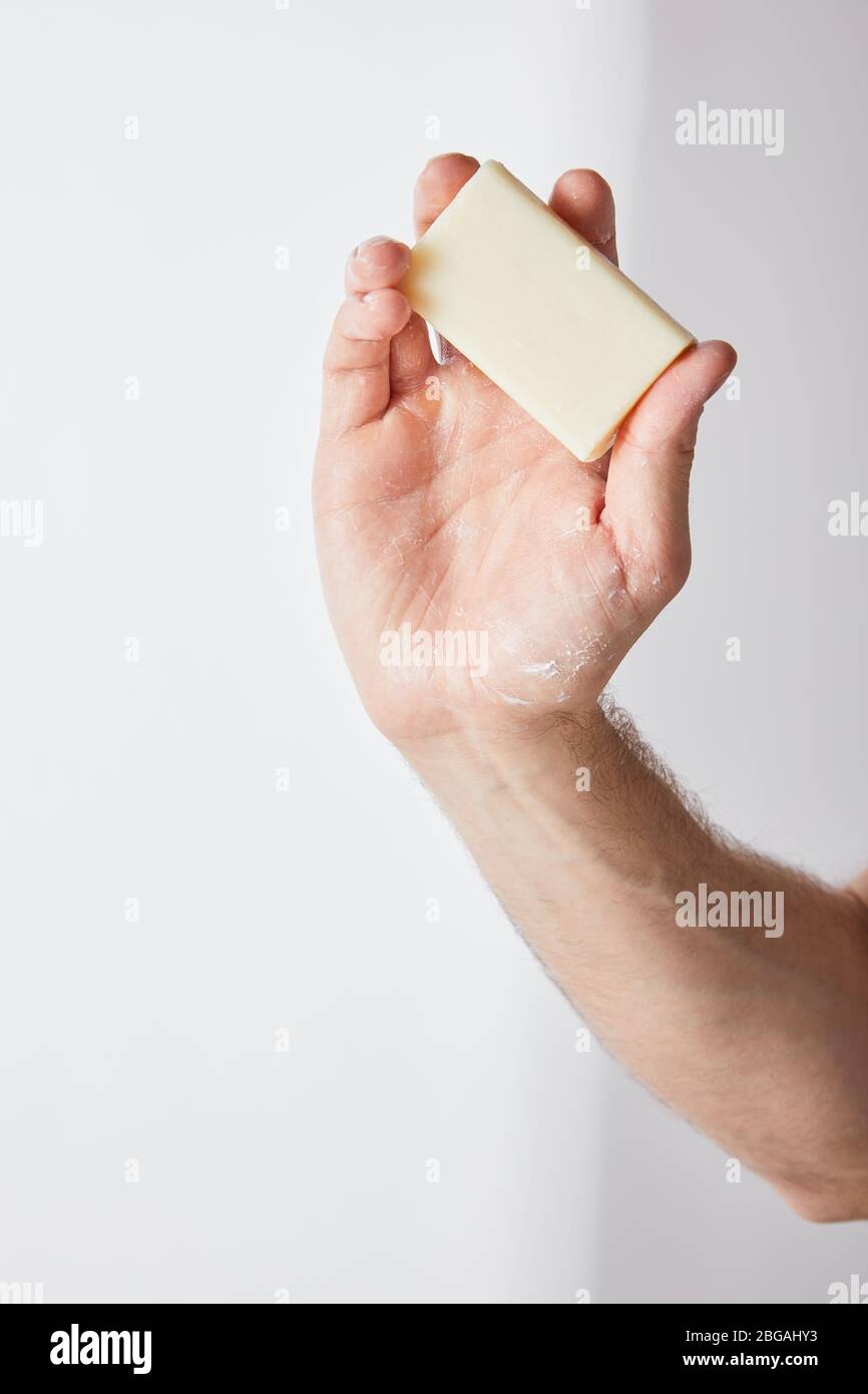 partial view of man holding soap in hand on grey background background ...