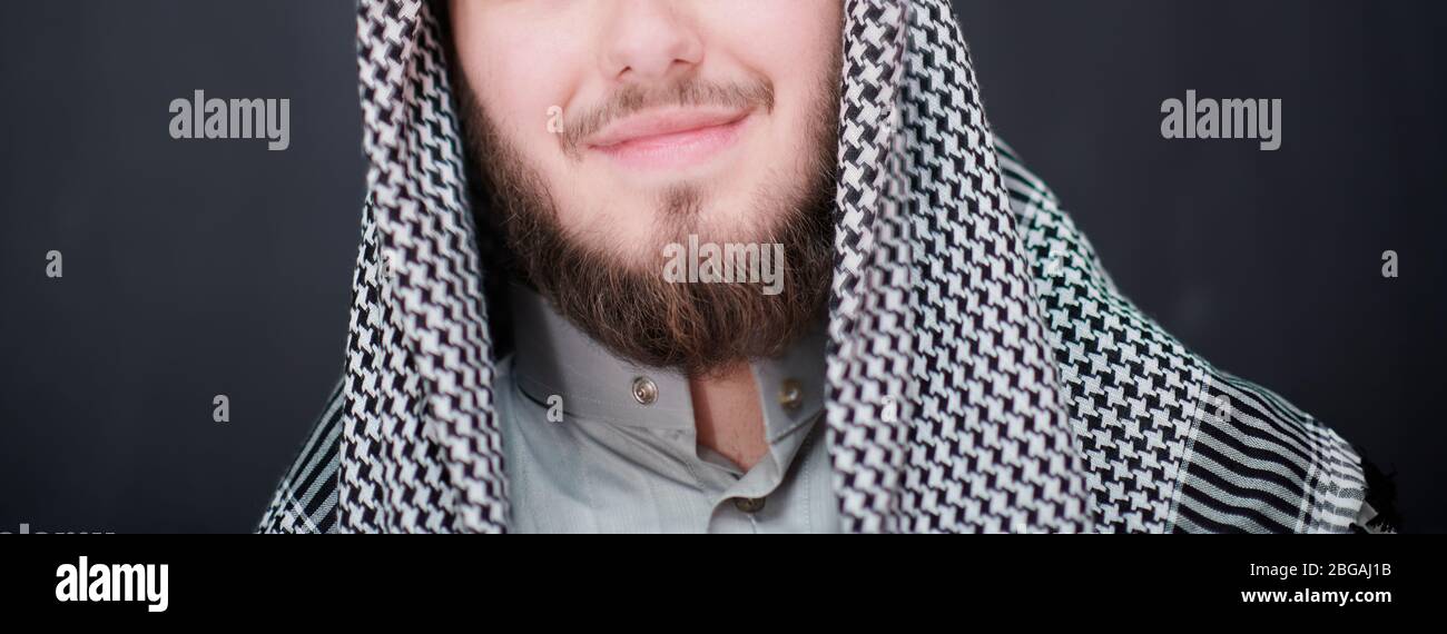 portrait of young arabian man in traditional clothes in front of black ...