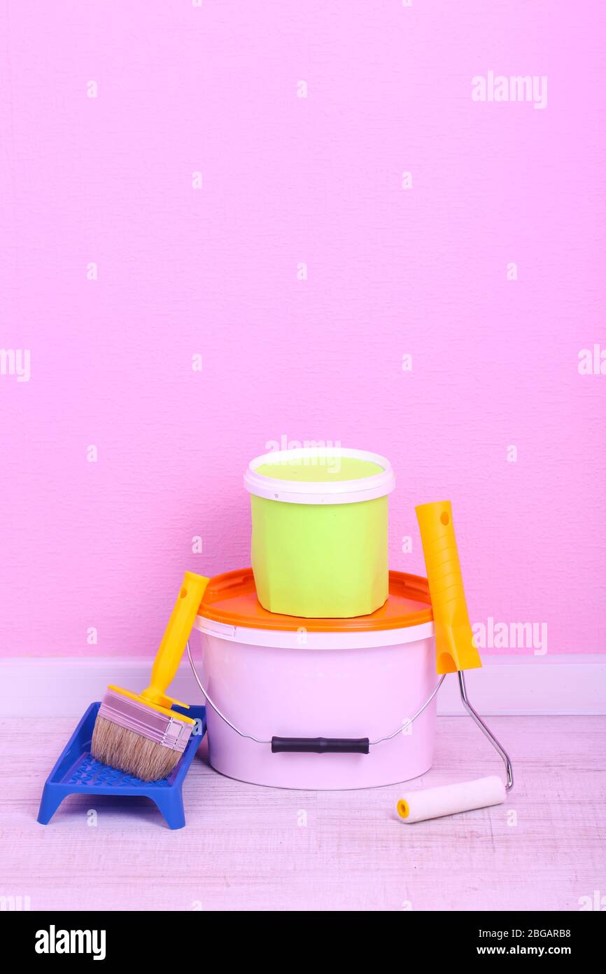 Paints, roll and paintbrush on floor in room on wall background Stock ...