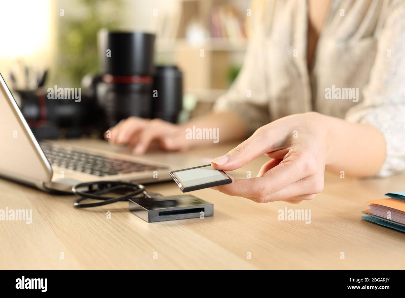 Close up of photographer woman hands plugging memory card to laptop on ...