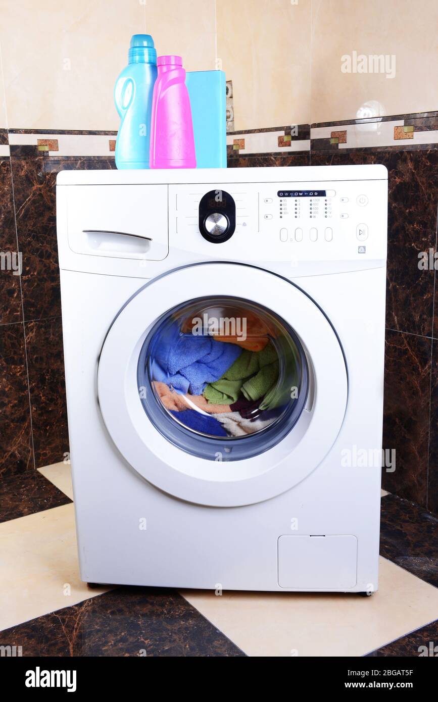 Washing machine loaded with clothes in bathroom Stock Photo - Alamy