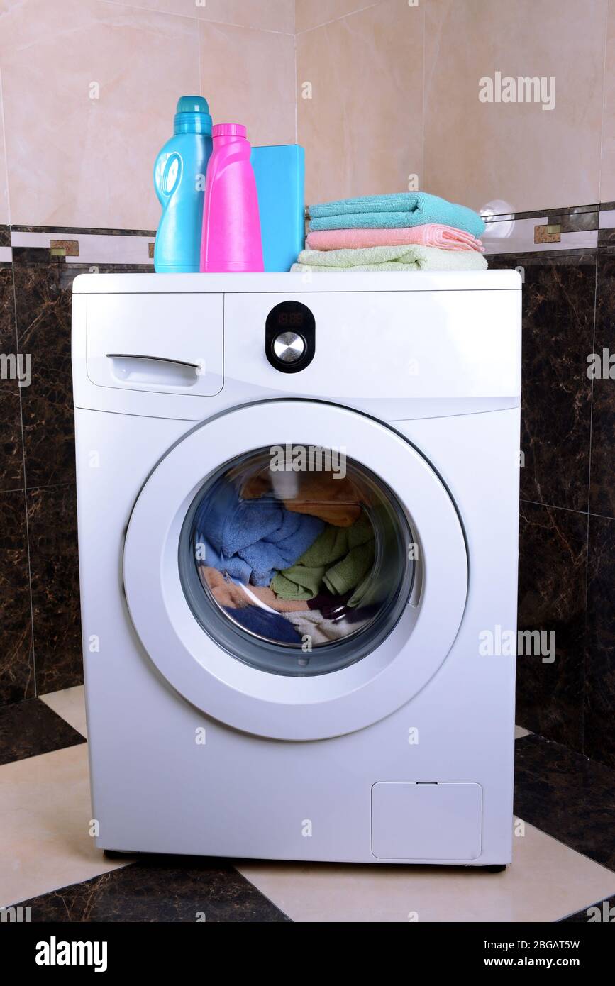 Washing machine loaded with clothes in bathroom Stock Photo - Alamy