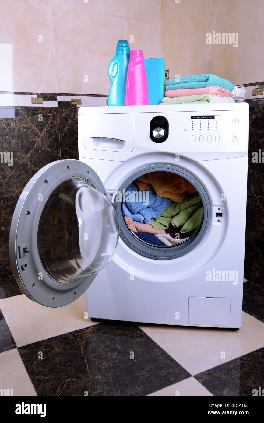 Washing machine loaded with clothes in bathroom Stock Photo - Alamy