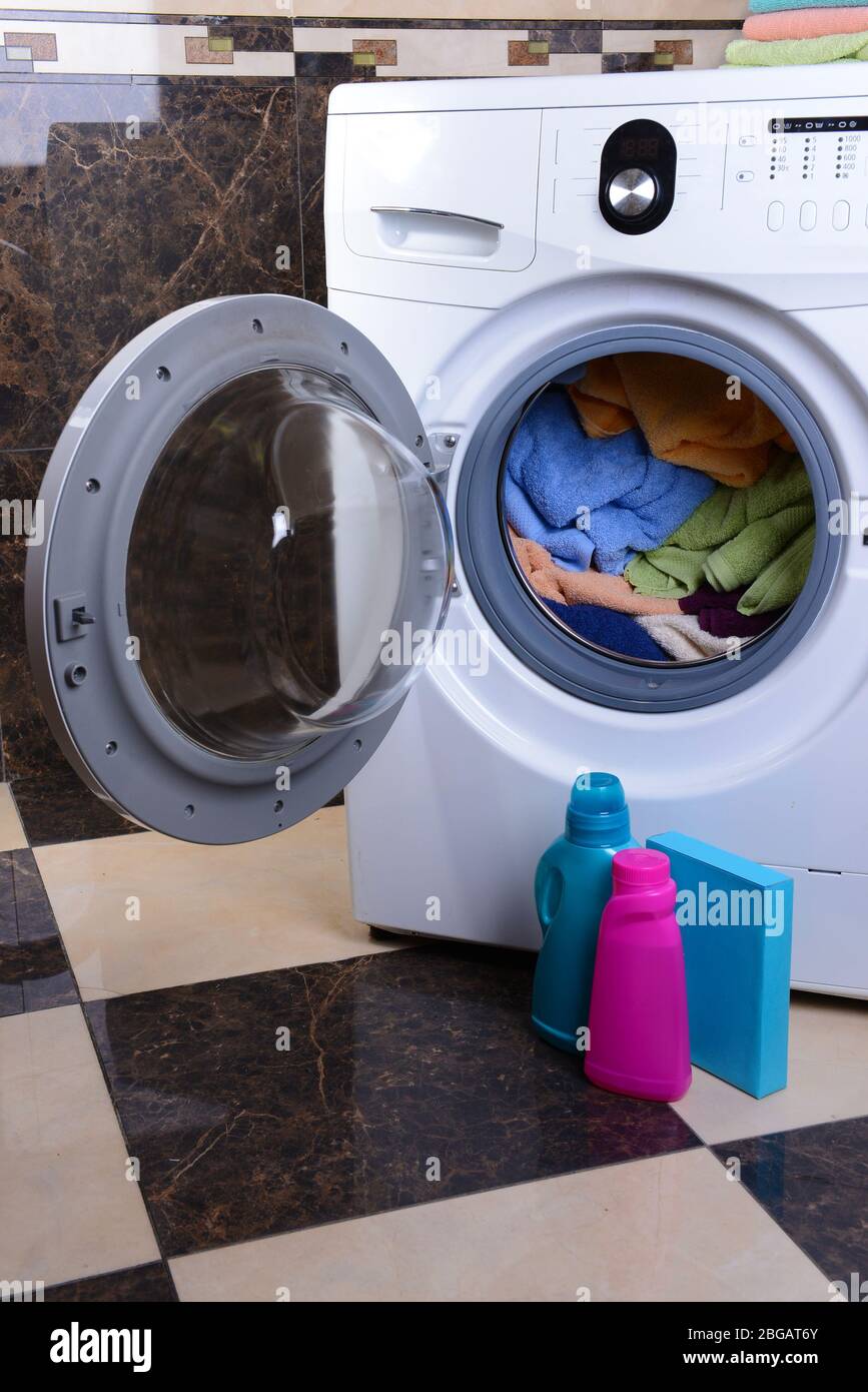 Washing machine loaded with clothes in bathroom Stock Photo - Alamy