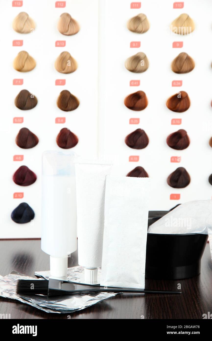 Hair dye kit and hair samples of different colors, on wooden table, on ...