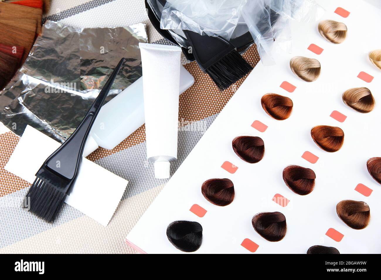 Hair dye kit on board with hair samples of different colors background ...