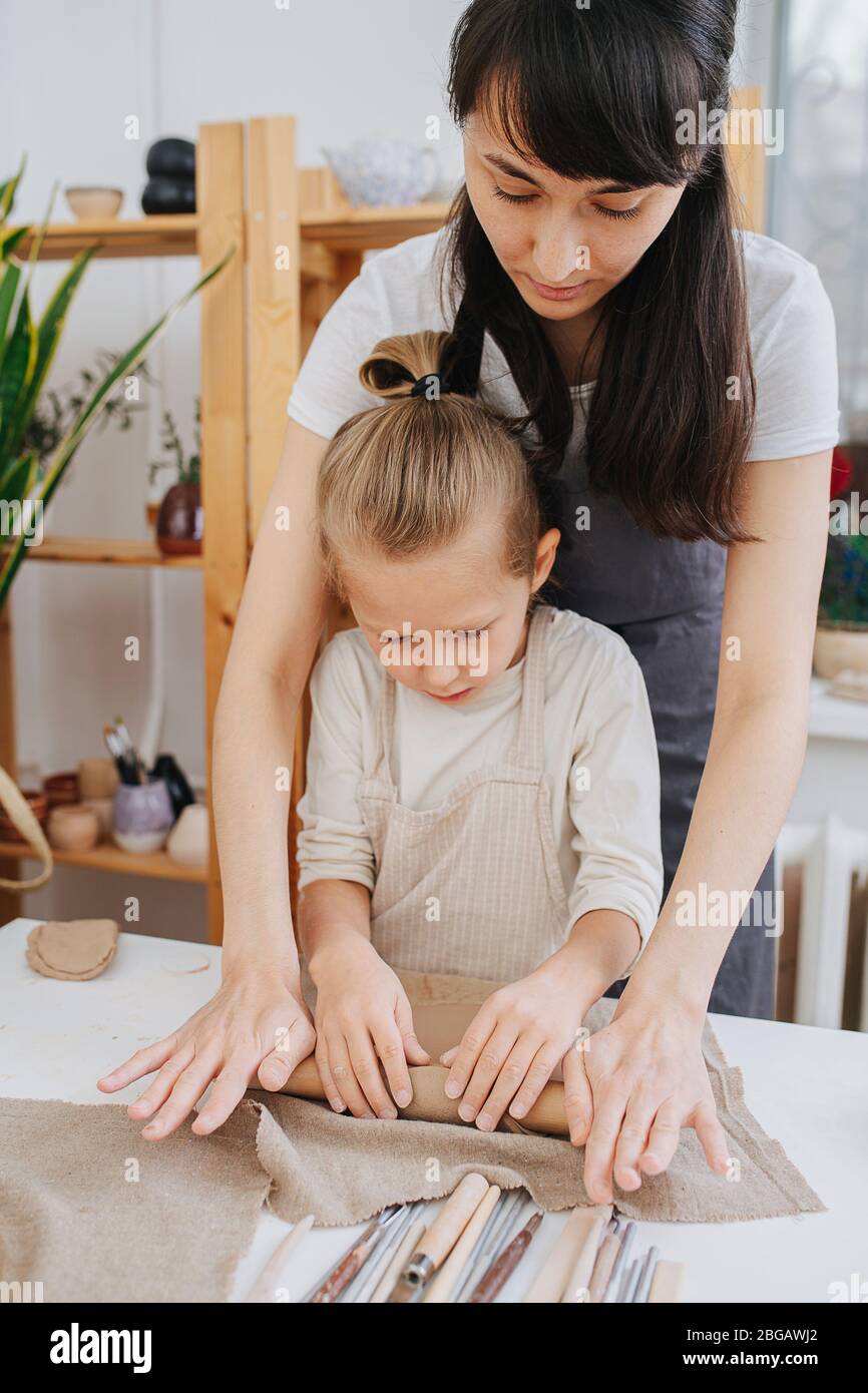 Potter teaches little boy how to roll clay. In a workshop Stock Photo ...
