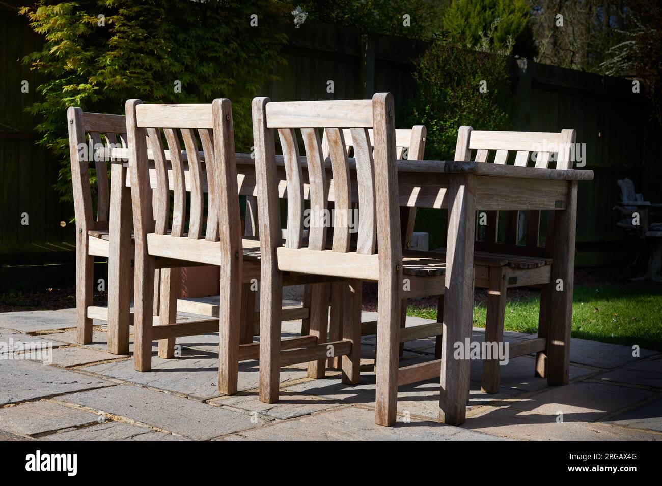 Wooden (iroko) garden table and chairs on a patio during a sunny day ...