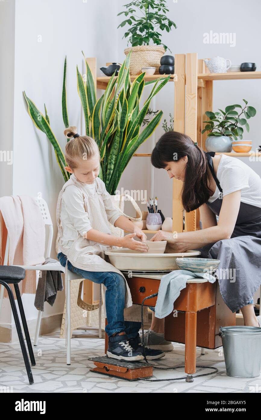 Potter teaches seven years old how to work with wheel Stock Photo - Alamy