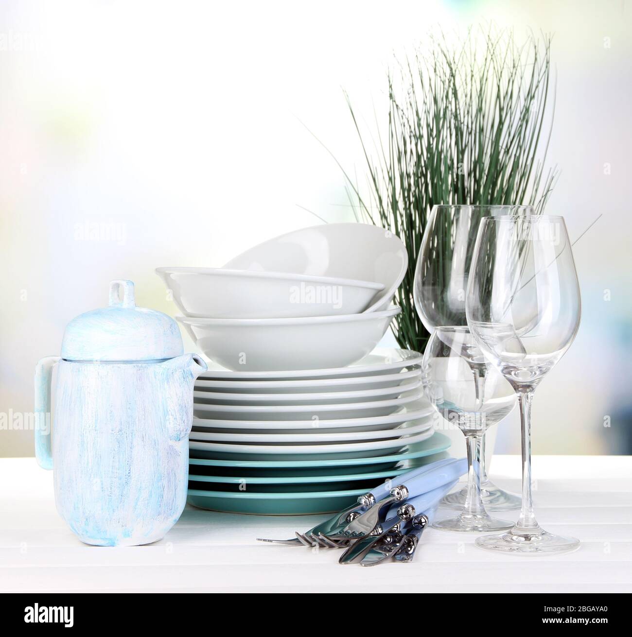 Clean dishes on table on bright background Stock Photo - Alamy