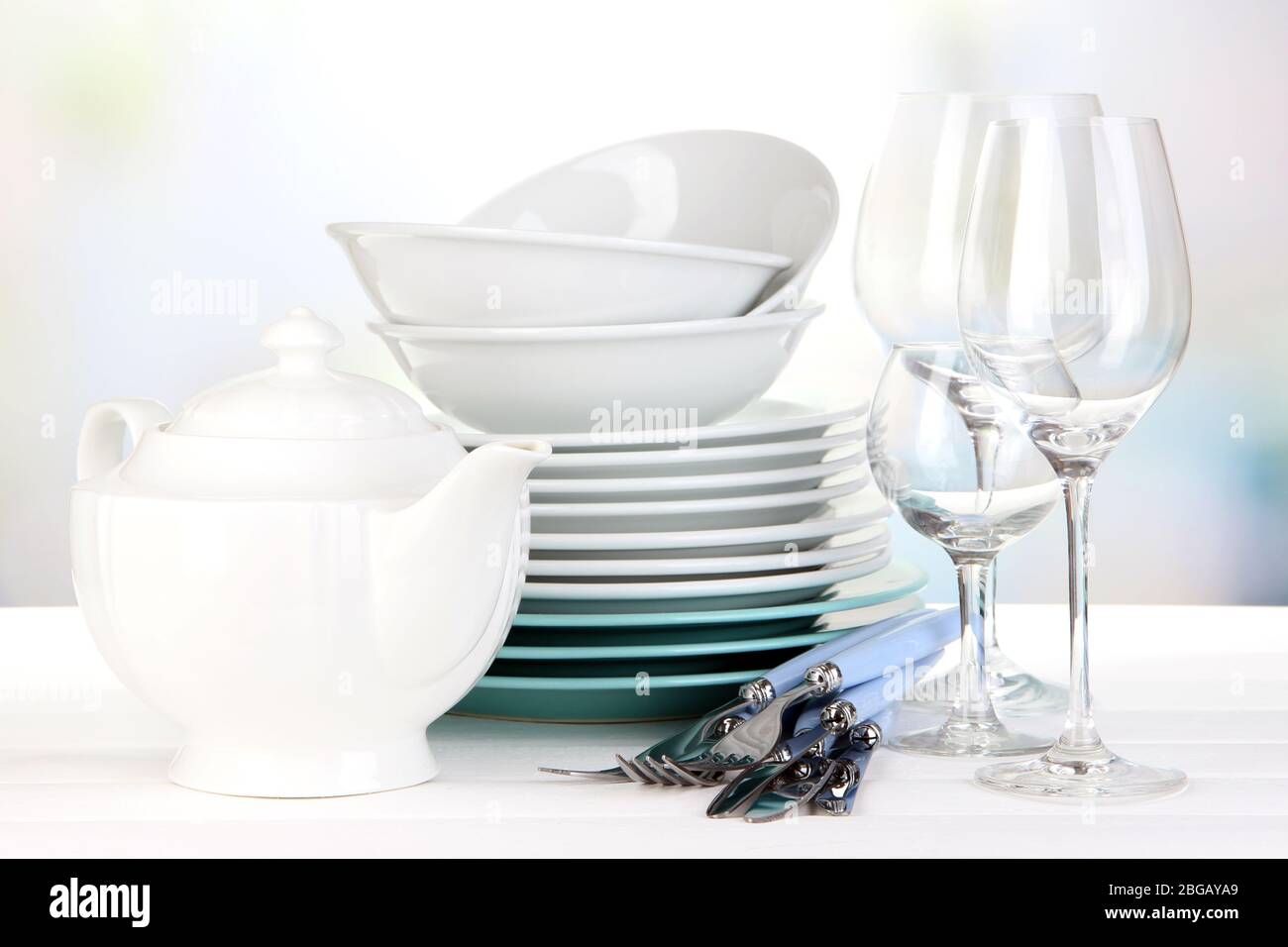 Clean dishes on table on bright background Stock Photo - Alamy