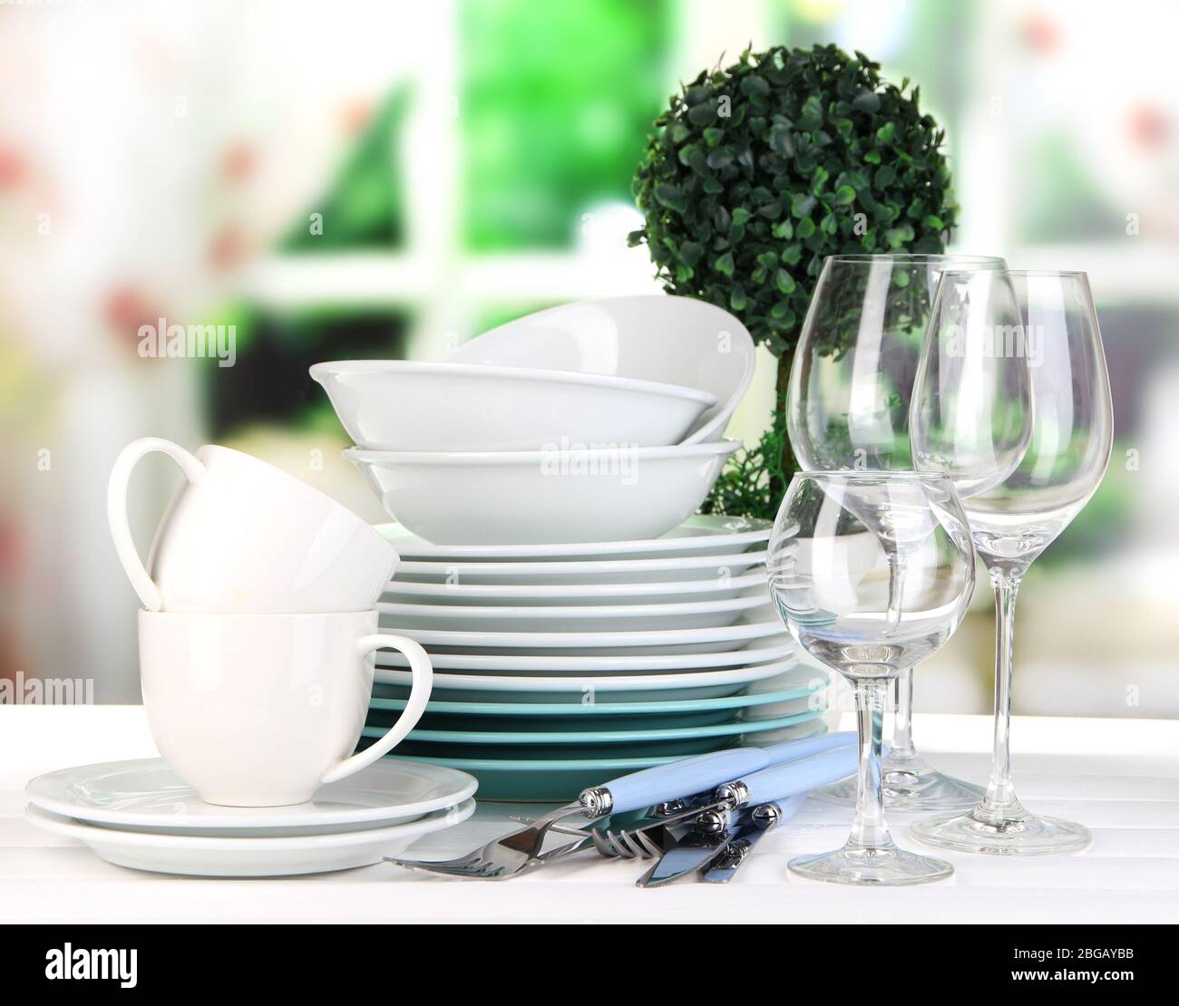Clean dishes on table on window background Stock Photo - Alamy