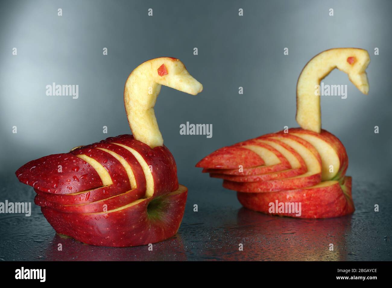 Carving fruit pattern of swan on grey wet background Stock Photo - Alamy