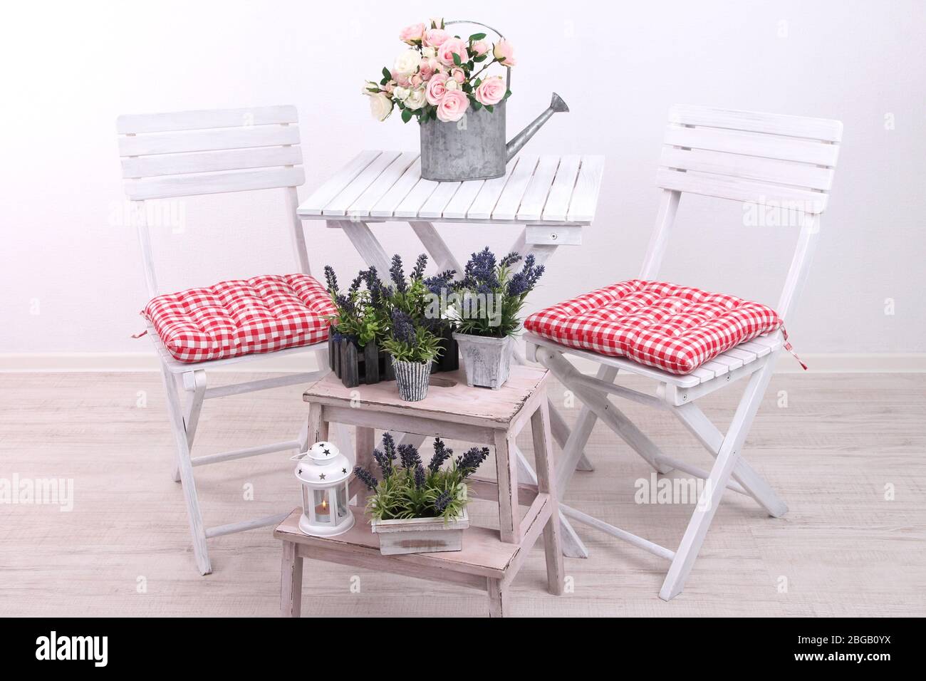 Garden chairs and table with flowers on wooden stand on white ...