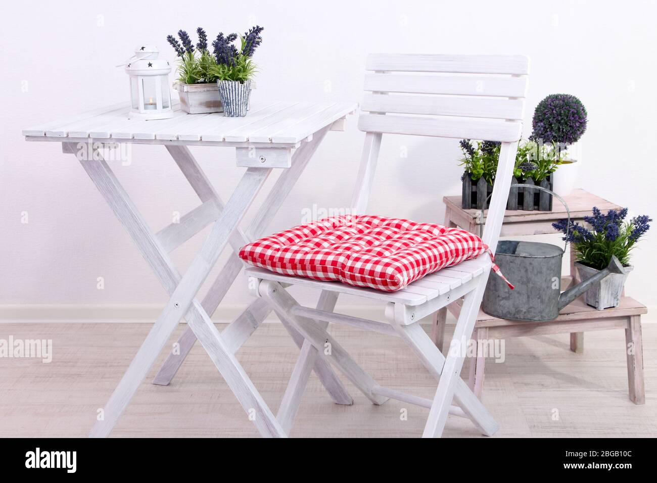 Garden chair and table with flowers on wooden stand on white background ...