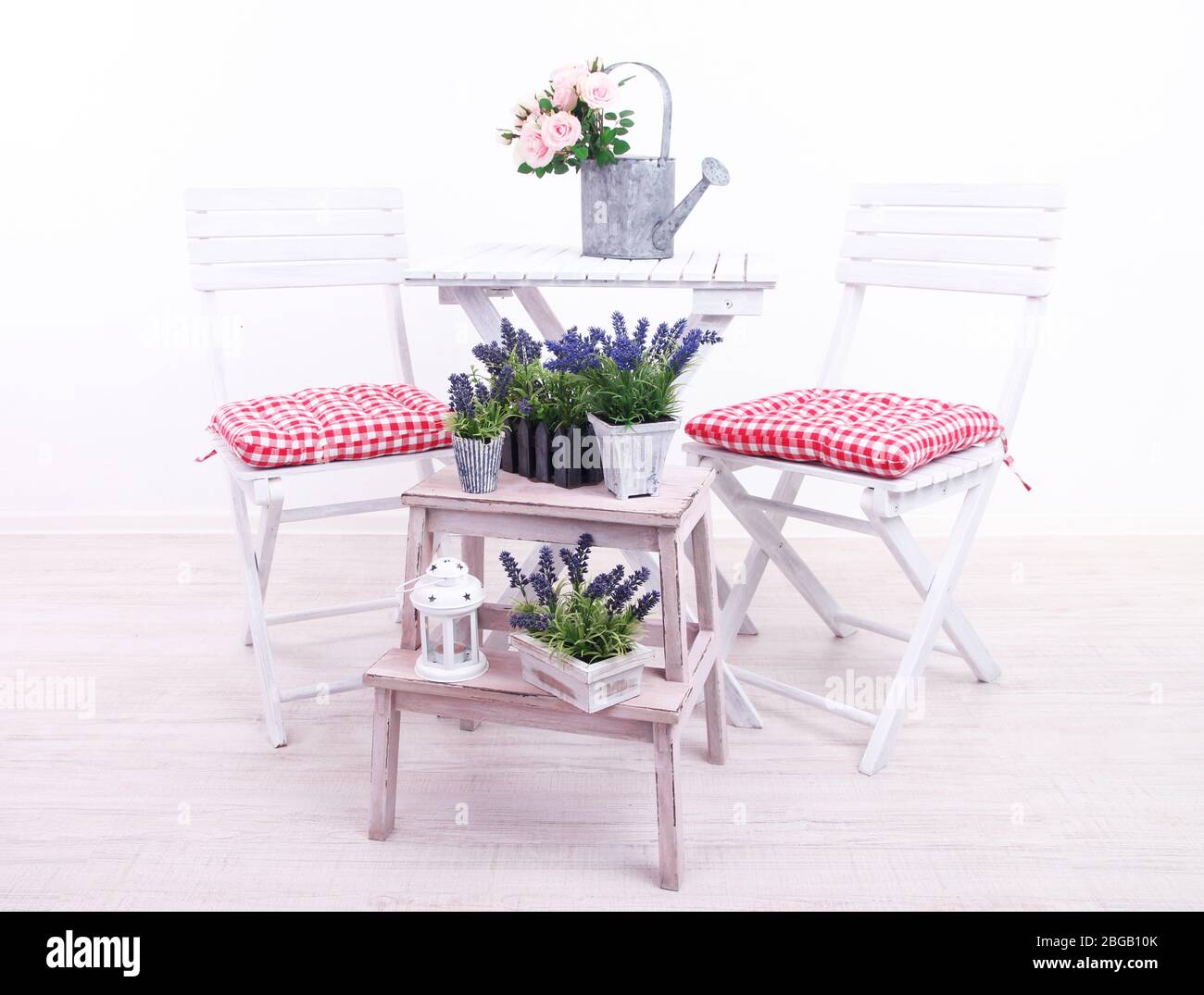 Garden chairs and table with flowers on wooden stand on white ...