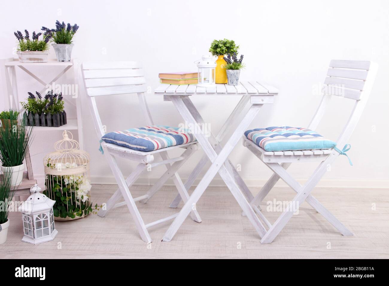 Garden chairs and table with flowers on wooden stand on white ...